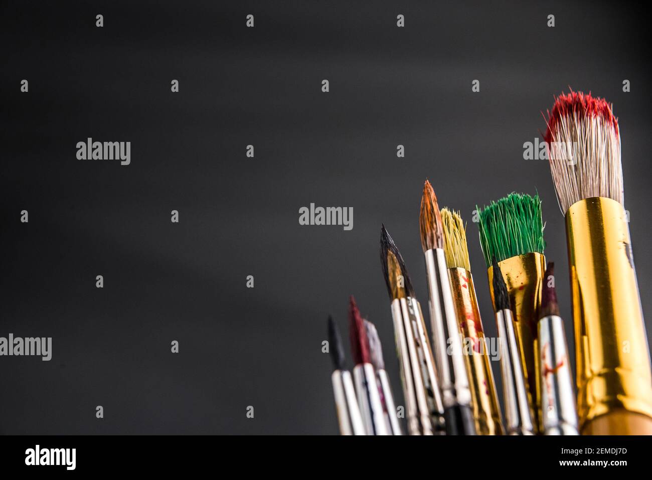 Artistic brushes with traces of paint on a dark background with a ...