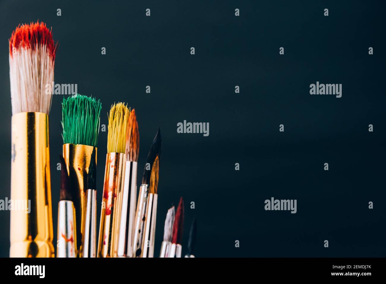 Artistic brushes with traces of paint on a dark background with a ...