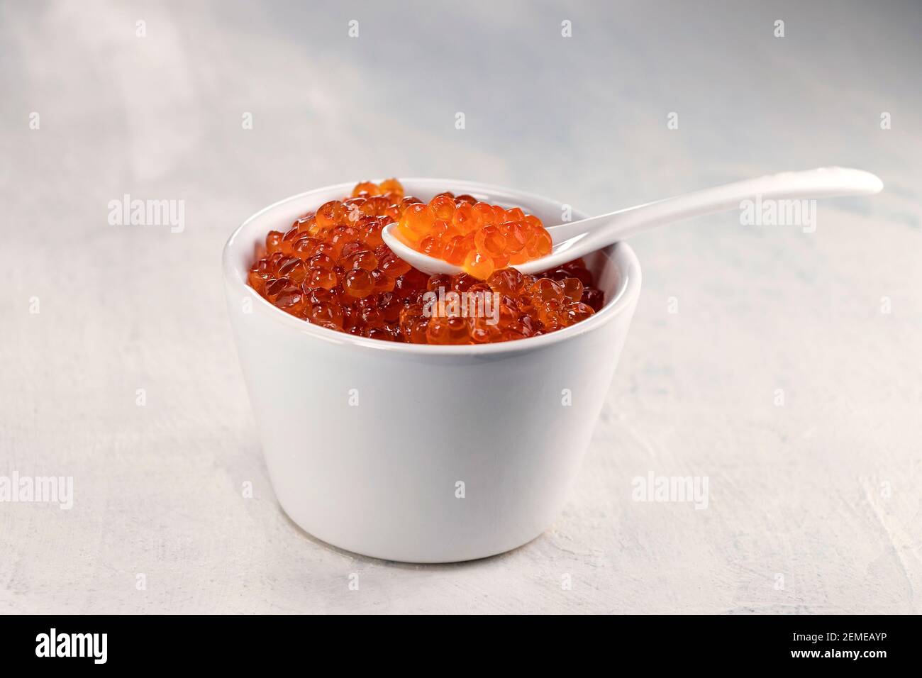 Delicious, crumbly, large red caviar in a white cup with a spoon on a ...