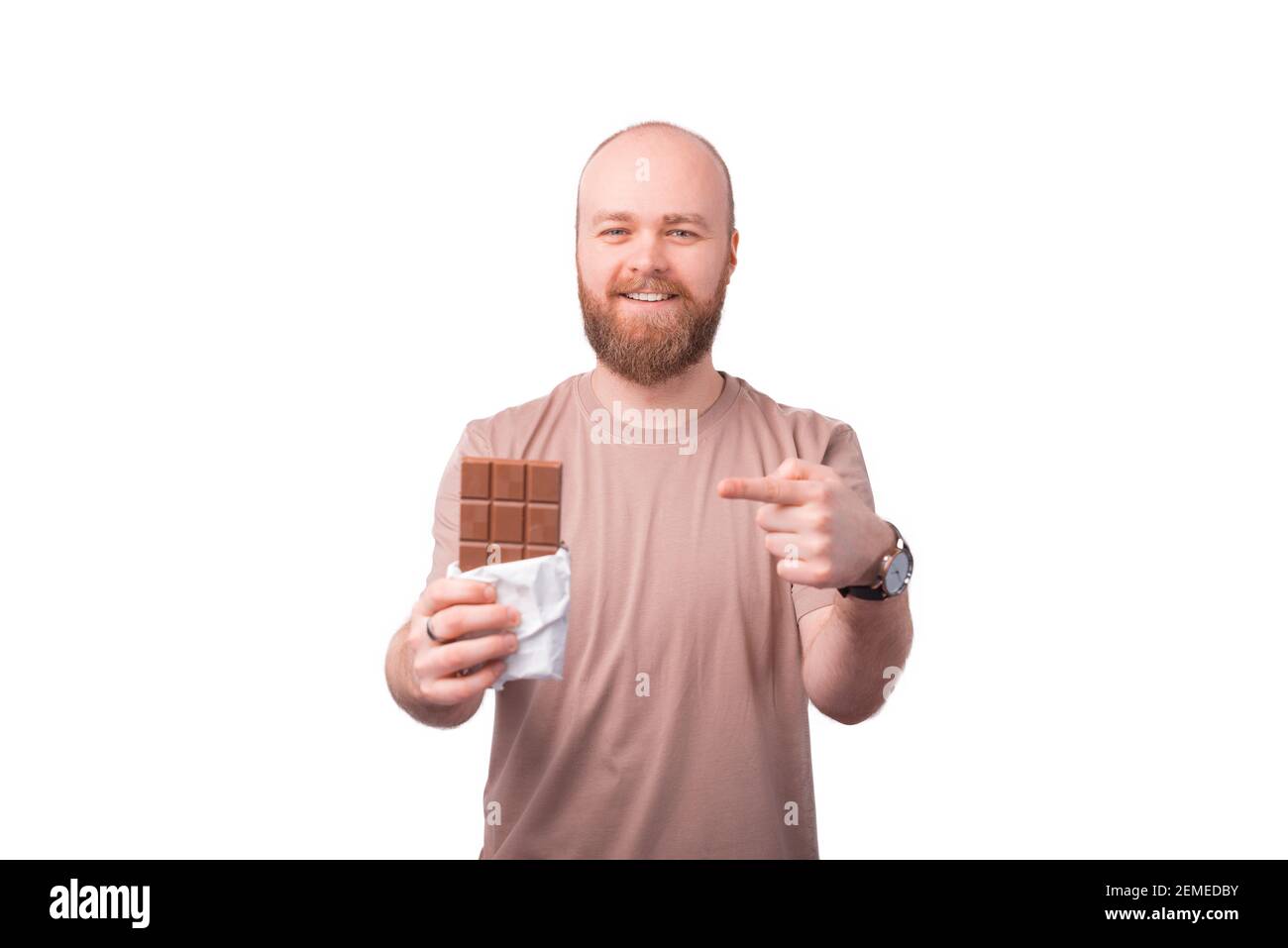 cheerful handsome man with beard pointing at block of chocolate ...
