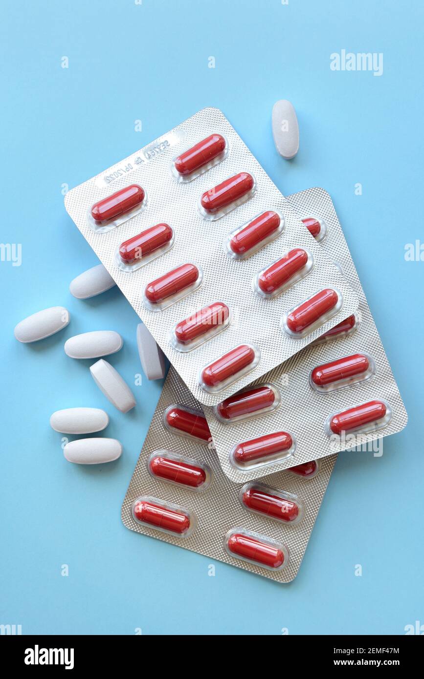 Assorted pharmaceutical medicine pills, tablets and capsules over blue ...