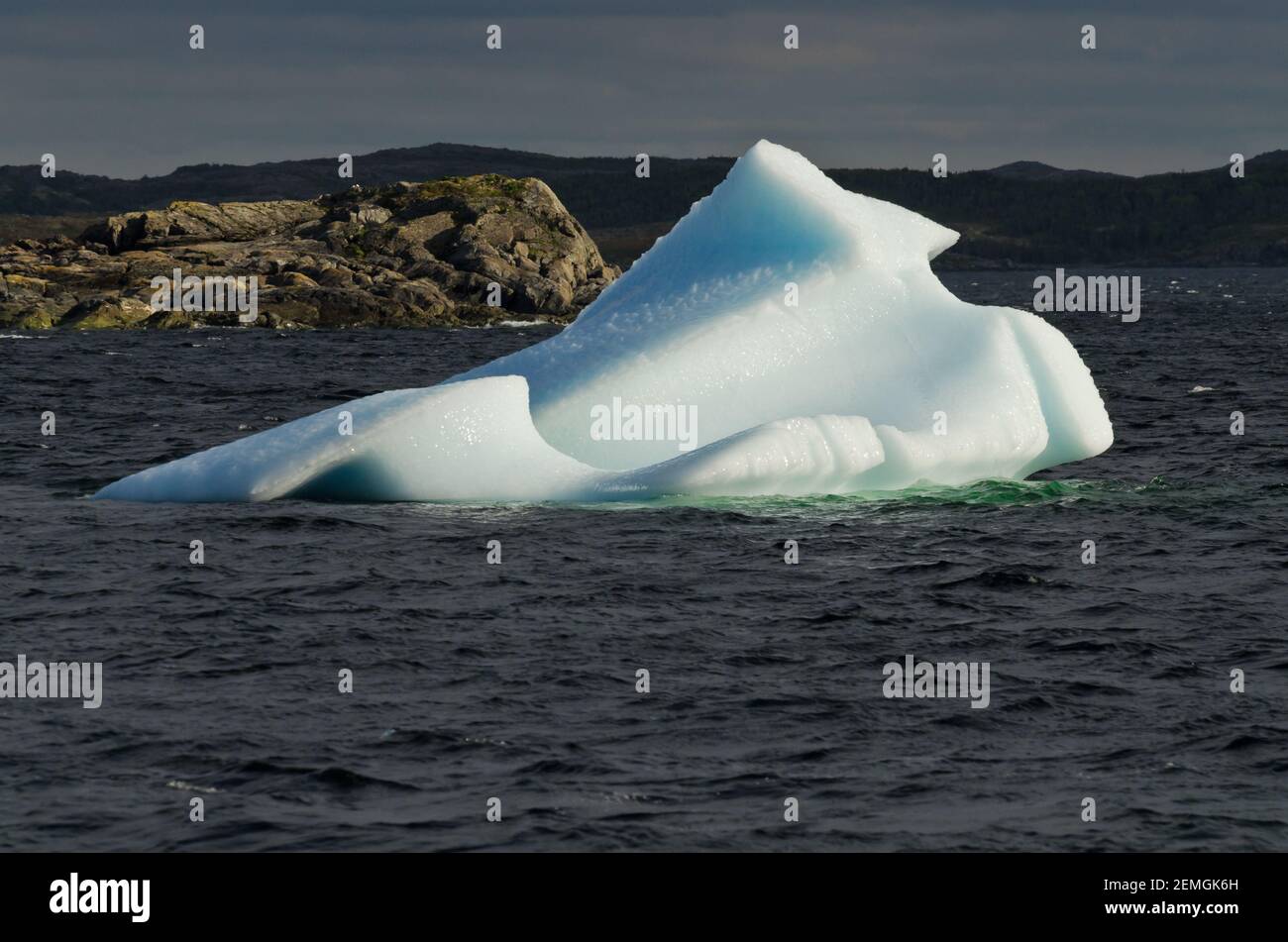 Bright white iceberg on dark water and rock background Stock Photo - Alamy