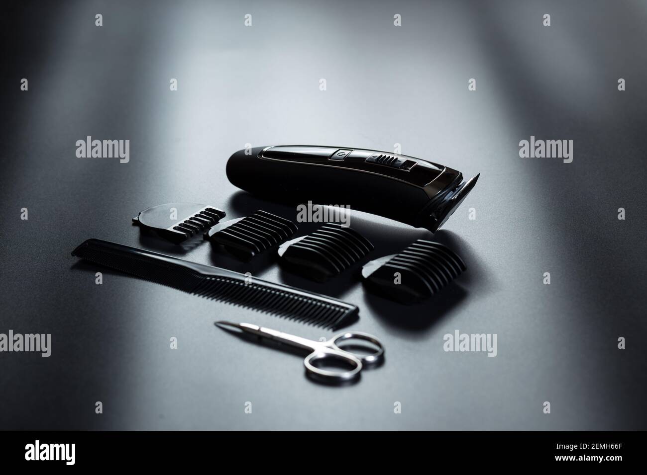 Electric trimmer with other barber tools on black background with light ...