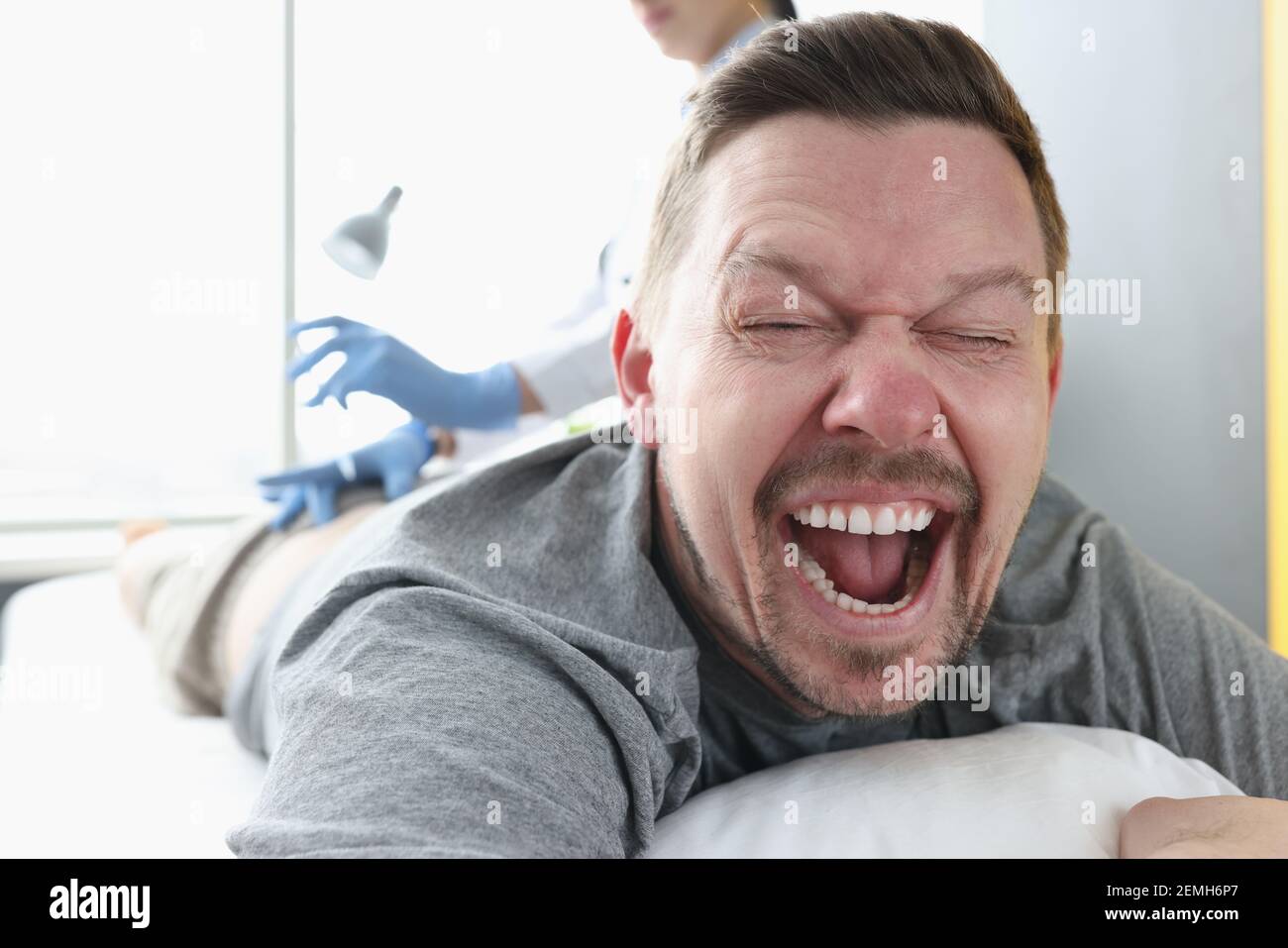 Man lying on couch with his mouth open. Nurse giving injection in ...