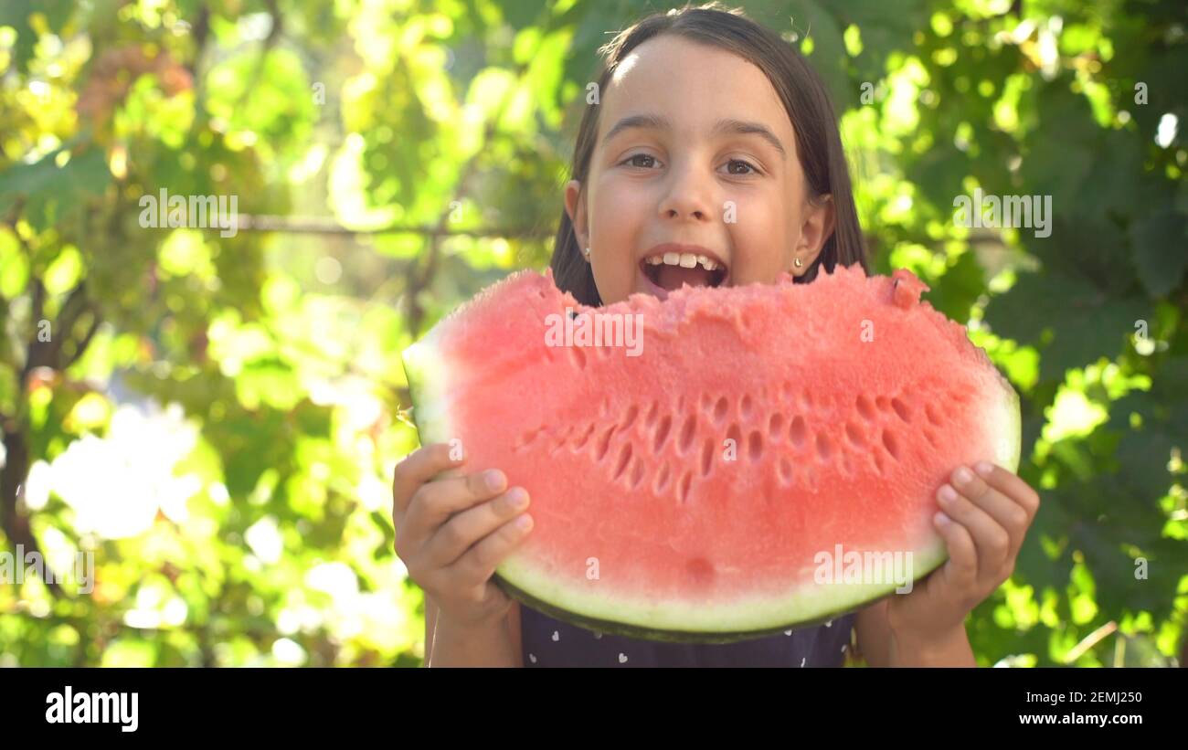 Happy child eating watermelon. Kid eat fruit outdoors. Little girl ...