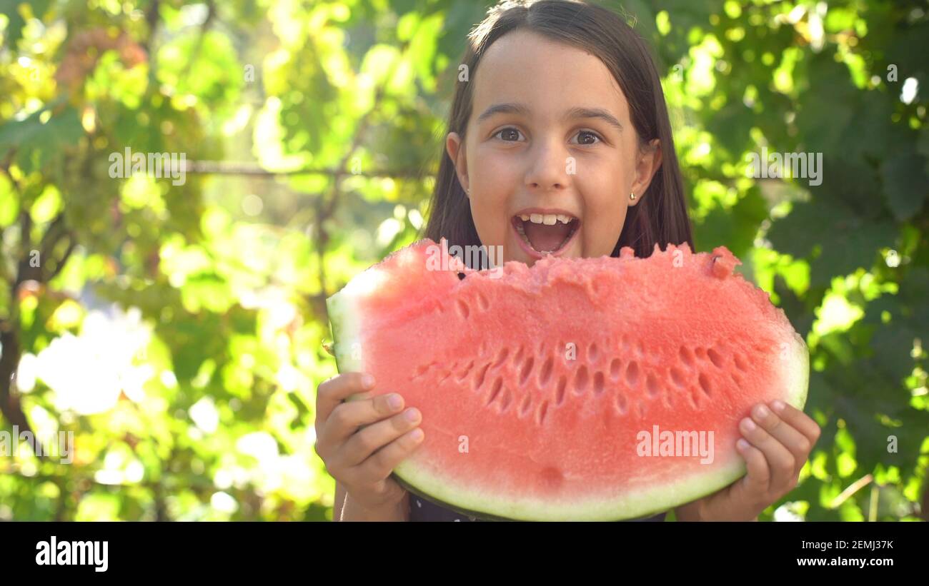 Happy child eating watermelon. Kid eat fruit outdoors. Little girl ...