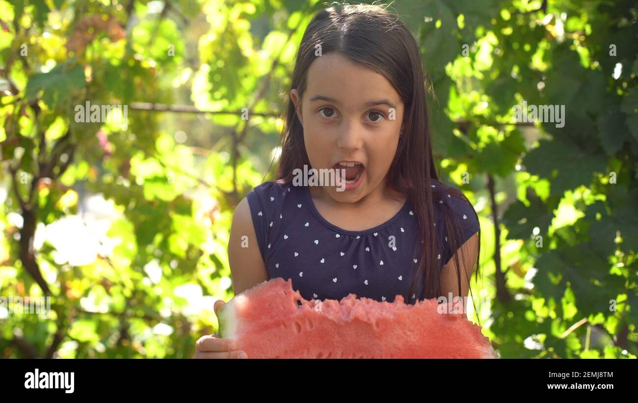 Happy child eating watermelon. Kid eat fruit outdoors. Little girl ...