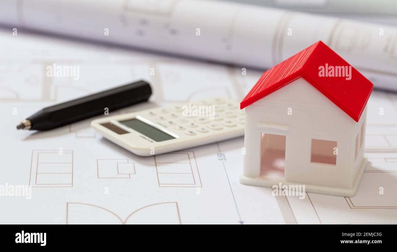 Calculator and architectural house model on blueprint plans background ...