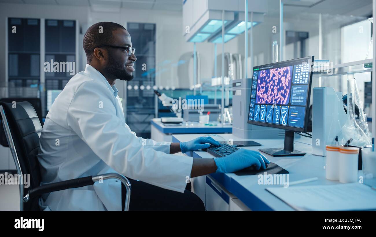 Modern Medical Laboratory: Male Scientist, Typing on Keyboard working on Computer, Scren Shows ...