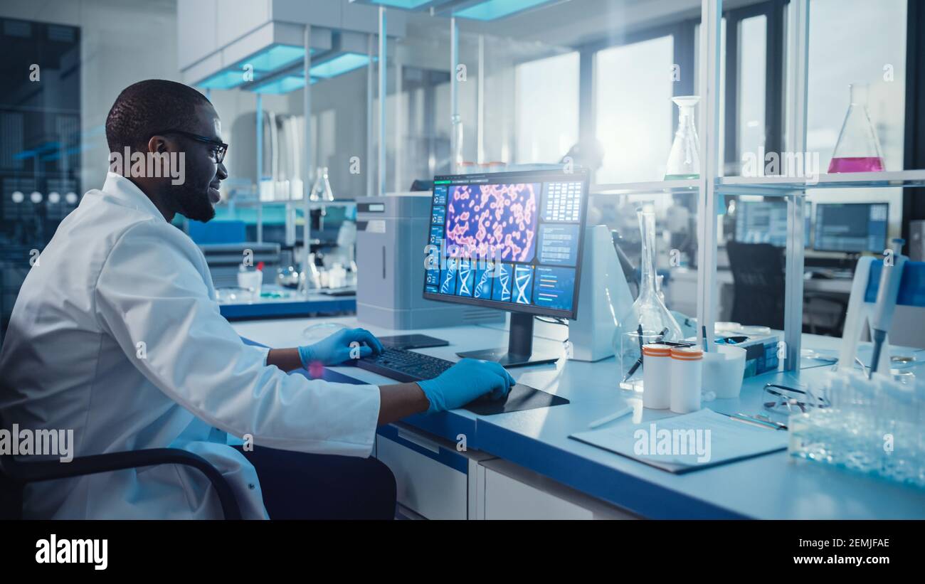 Modern Medical Laboratory: Male Scientist, Typing on Keyboard working on Computer, Scren Shows ...