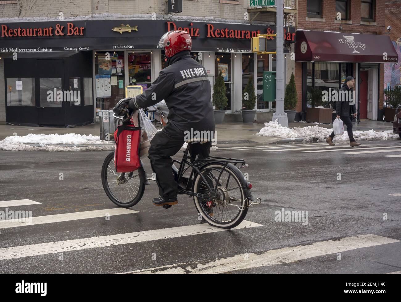 A deliveryman from GrubHub on his electric bike crosses Fulton Street ...
