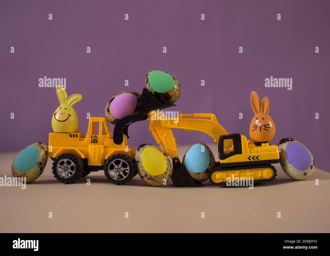 toy orange excavator and loader with colorful Easter quail eggs and ...