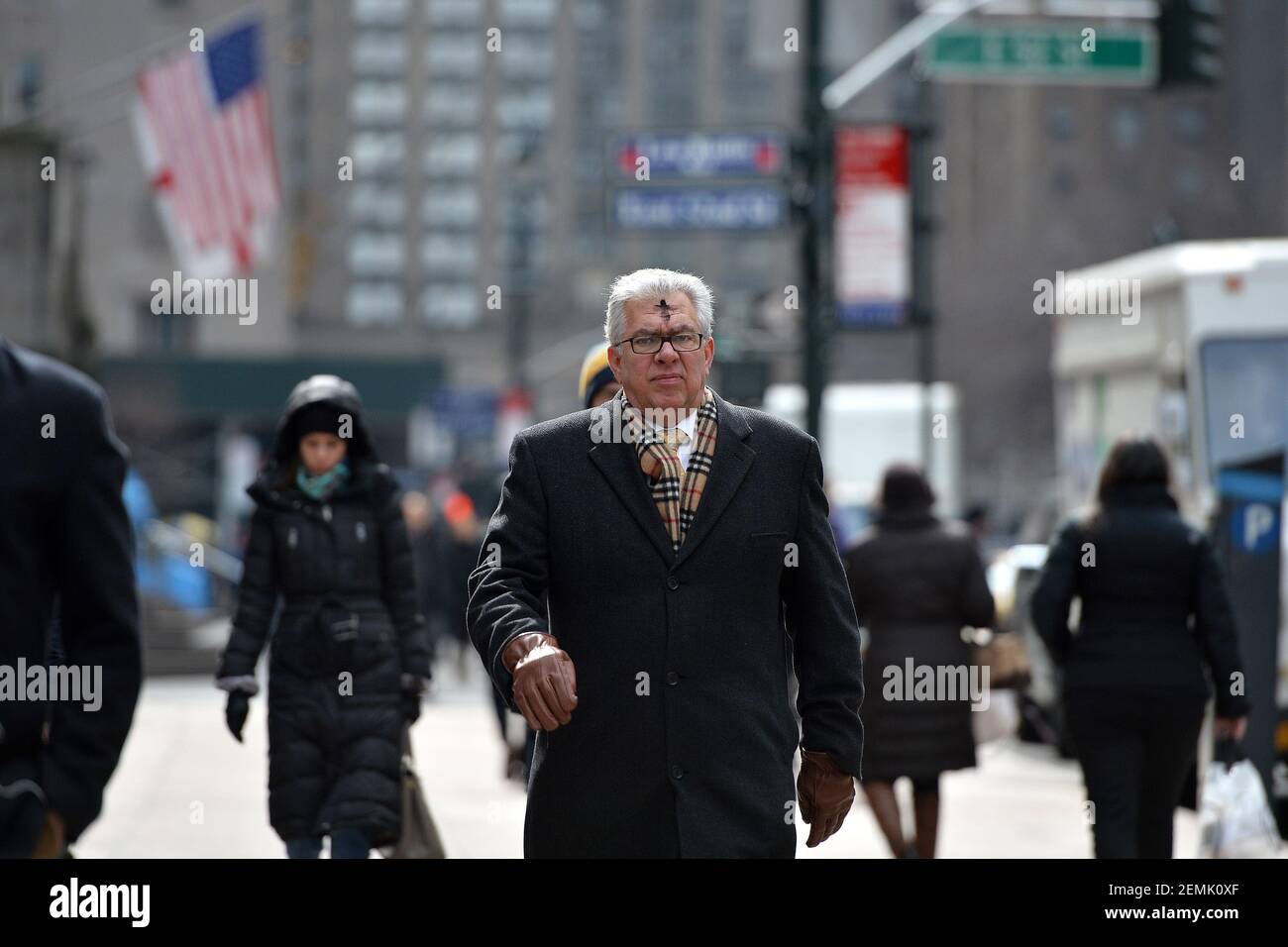 A man walks down Park Avenue with a cross of black ashes on his ...