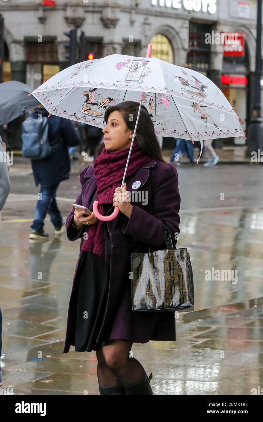 A woman is seen sheltering from the rain beneath an umbrella during ...