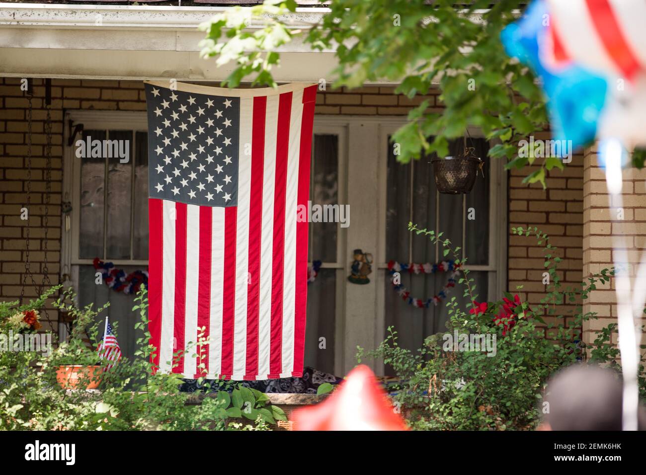 American Flag hanging from front porch of house Stock Photo - Alamy