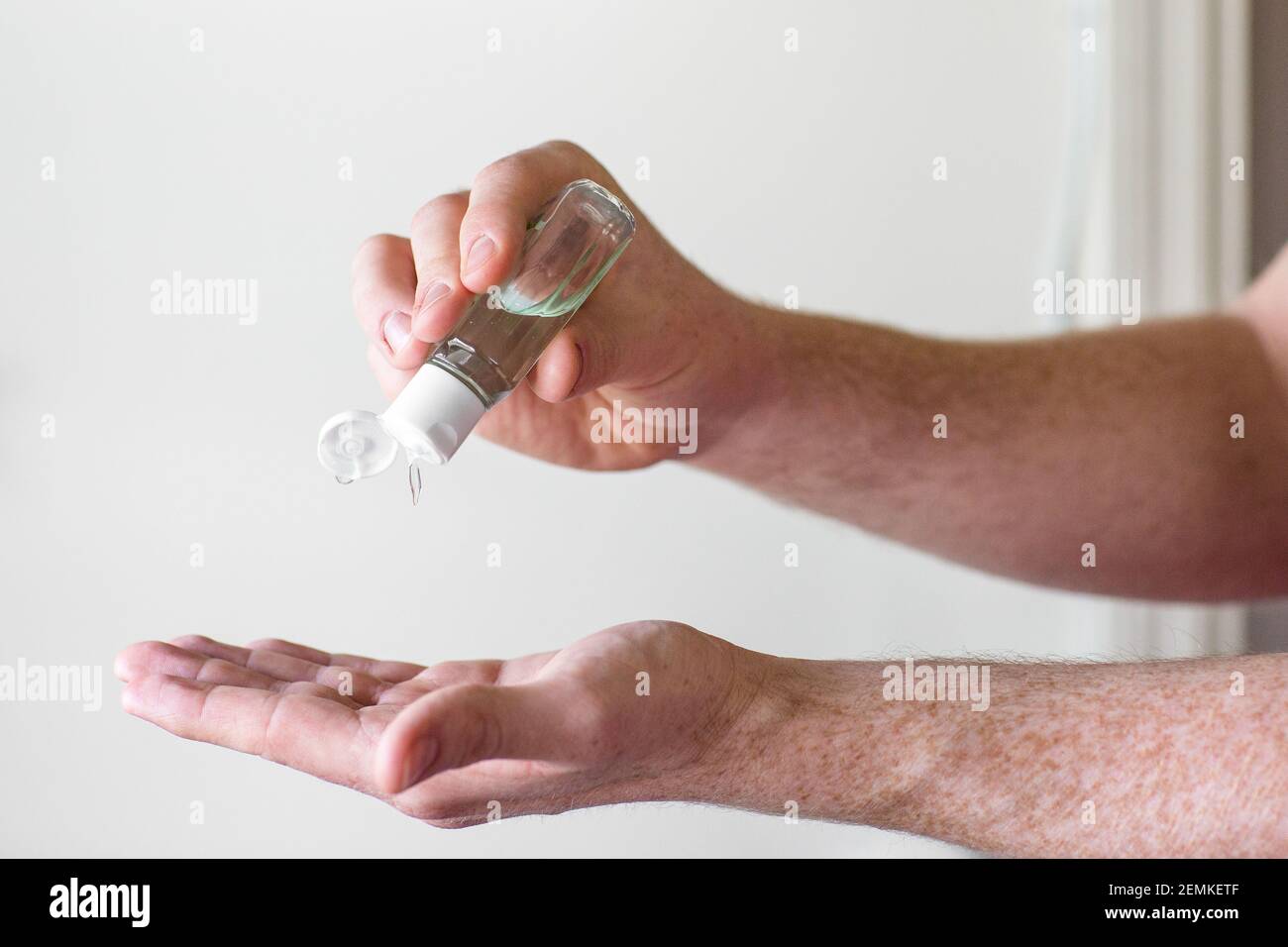 Closeup of man's hands squirting hand sanitizer from a small clear ...