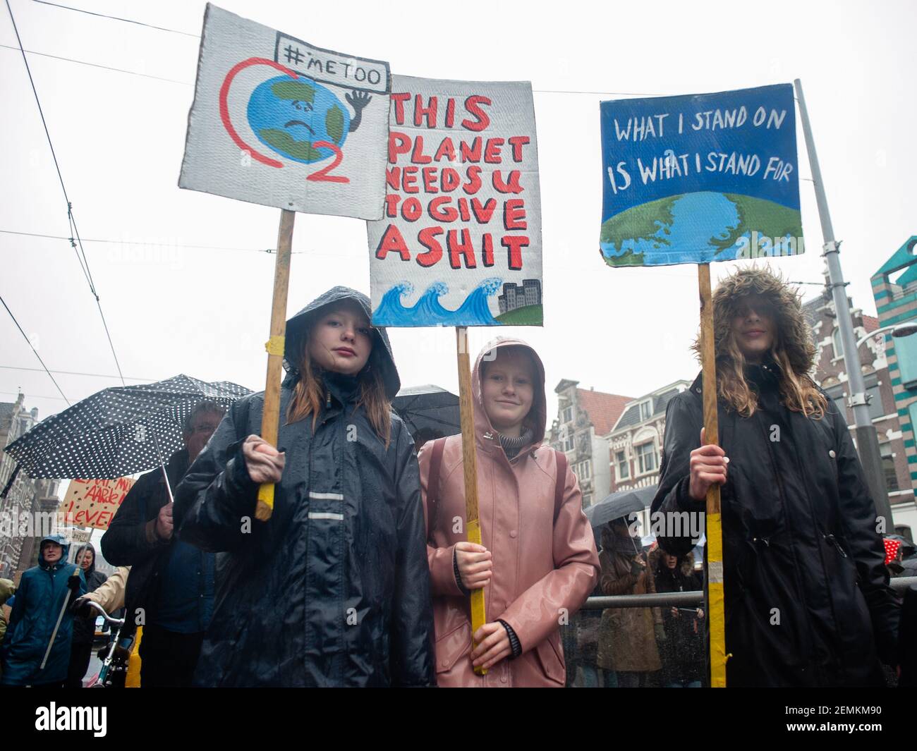 Three little girls are holding placards under the rain during the ...