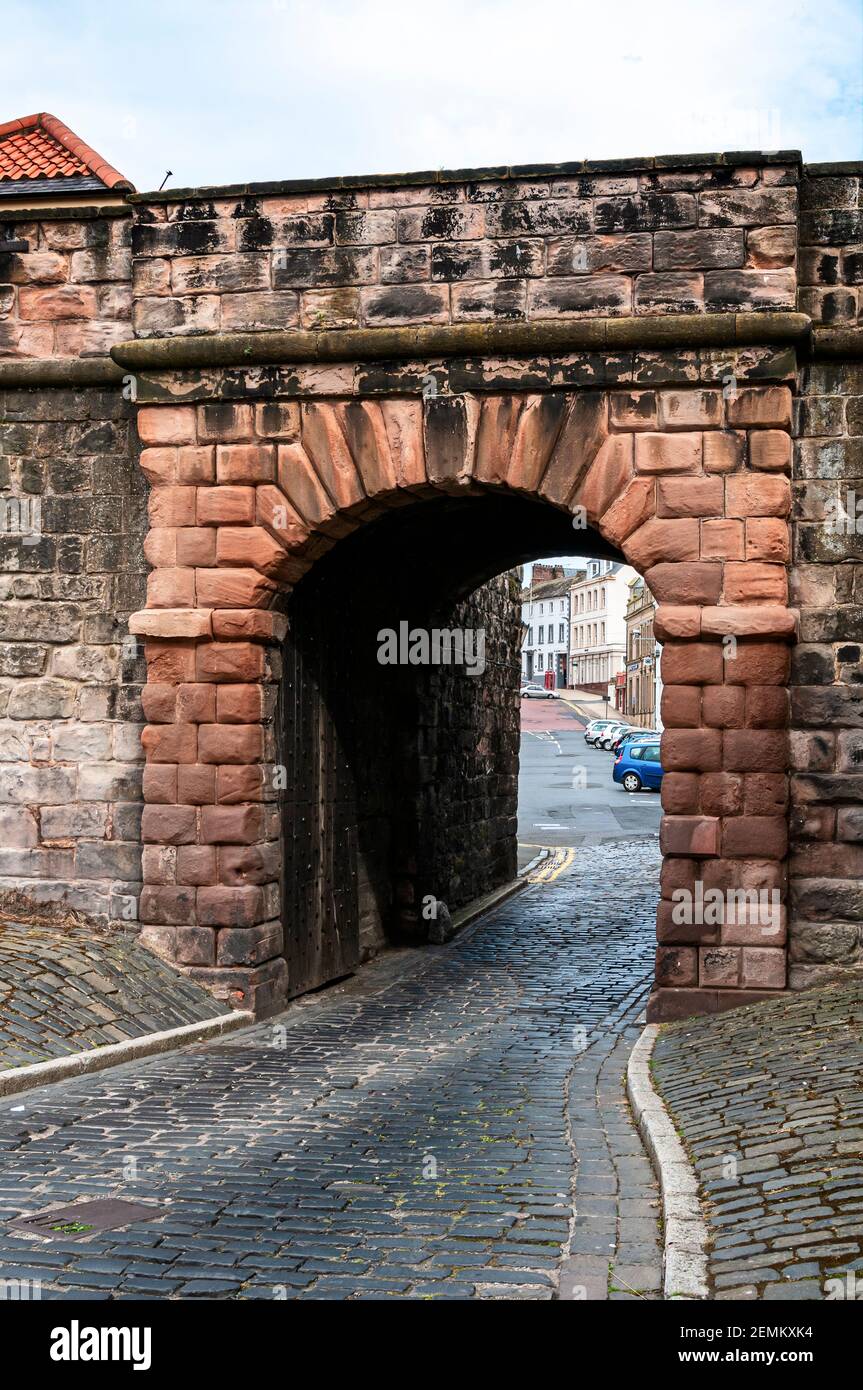A narrow road passes under an attractive red sandstone arched bridge ...