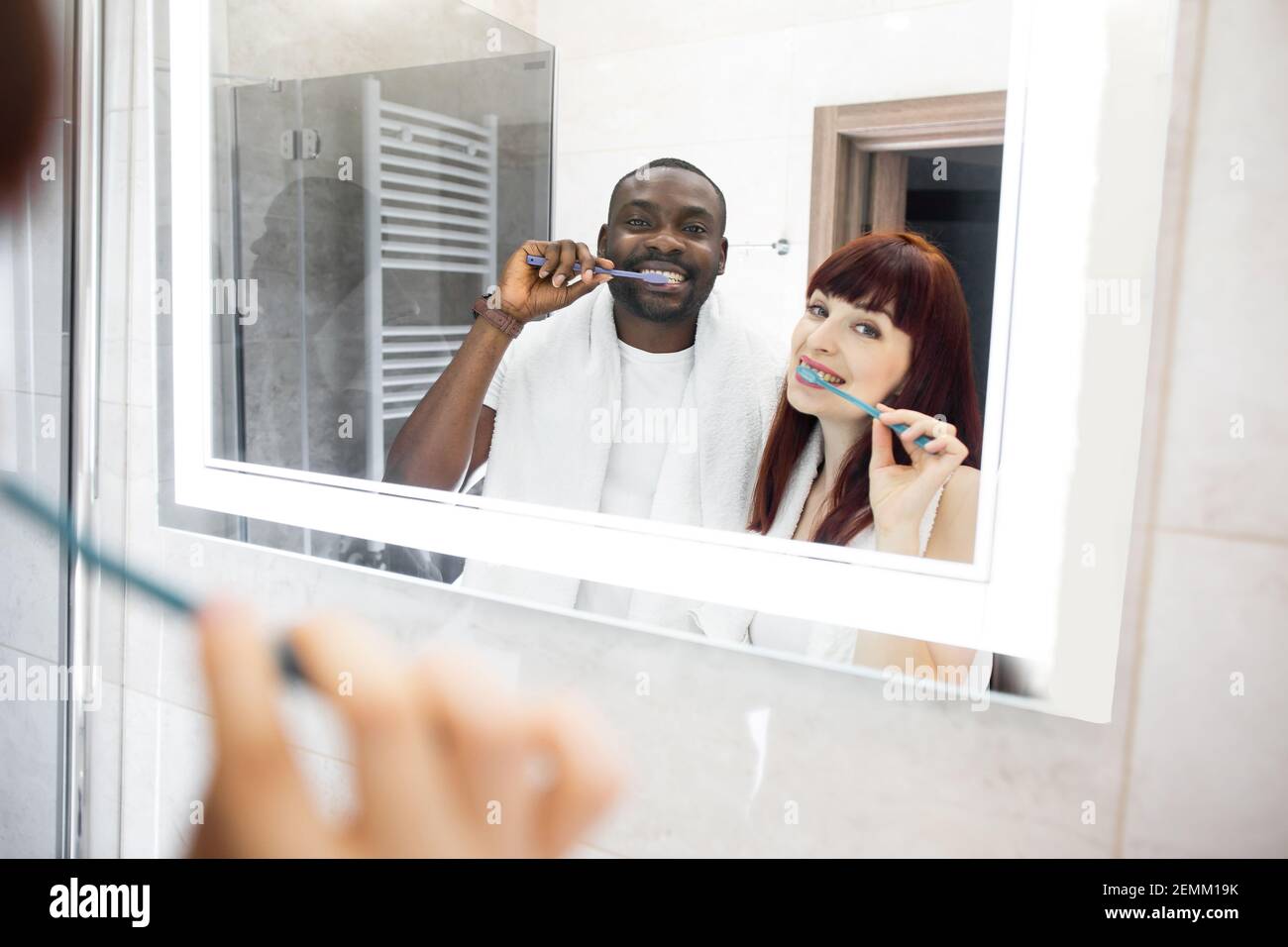 In the bathroom. Joyful positive multiracial couple standing in front ...