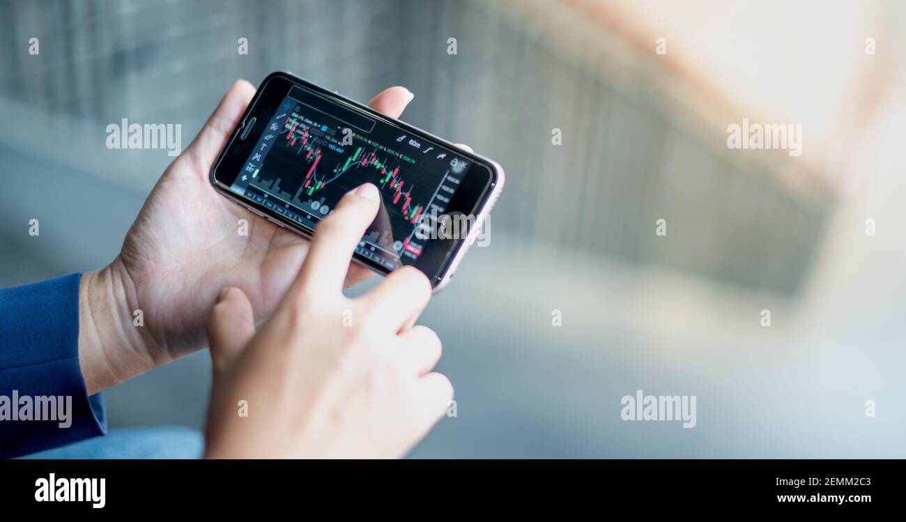 Close-up hand holding mobile phone with analyzing graph and the ...