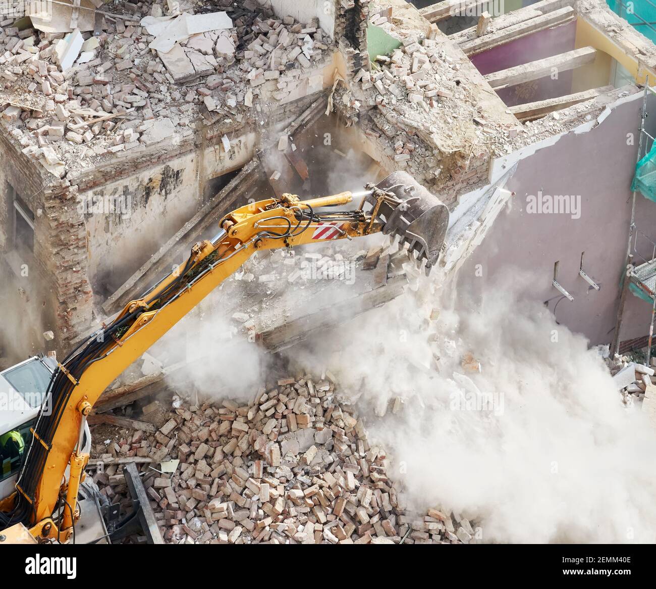 Old brick building demolition with an excavator bucket in dust cloud, view from above Stock ...