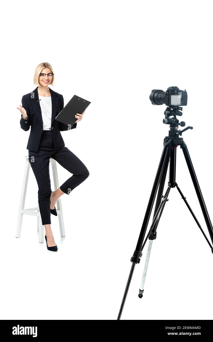 full length view of smiling news anchor on high stool pointing with ...