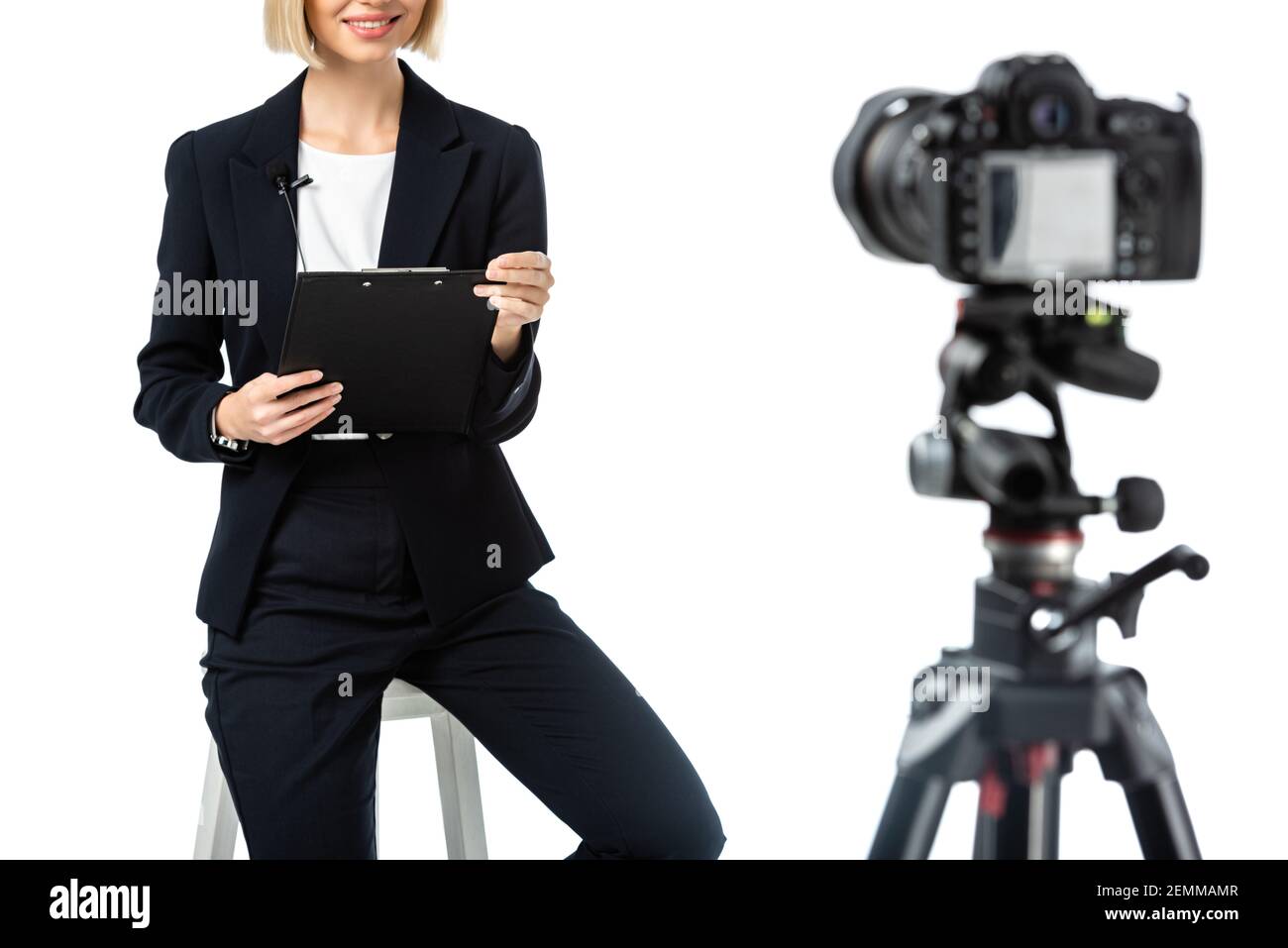 cropped view of smiling anchorwoman with clipboard sitting near digital ...