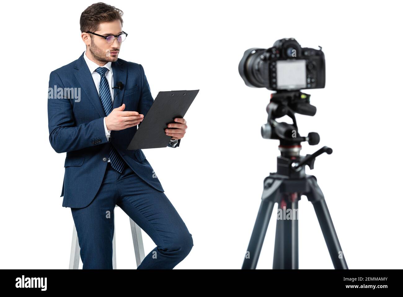 news anchor pointing at clipboard while sitting on high stool near ...