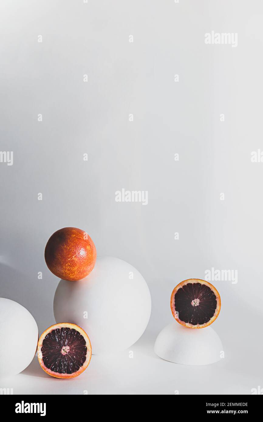 Creative still life with red orange fruits and white geometric shapes ...