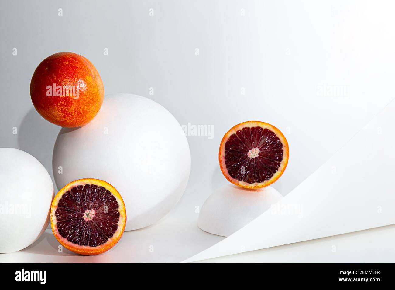 Creative still life with red orange fruits and white geometric shapes ...