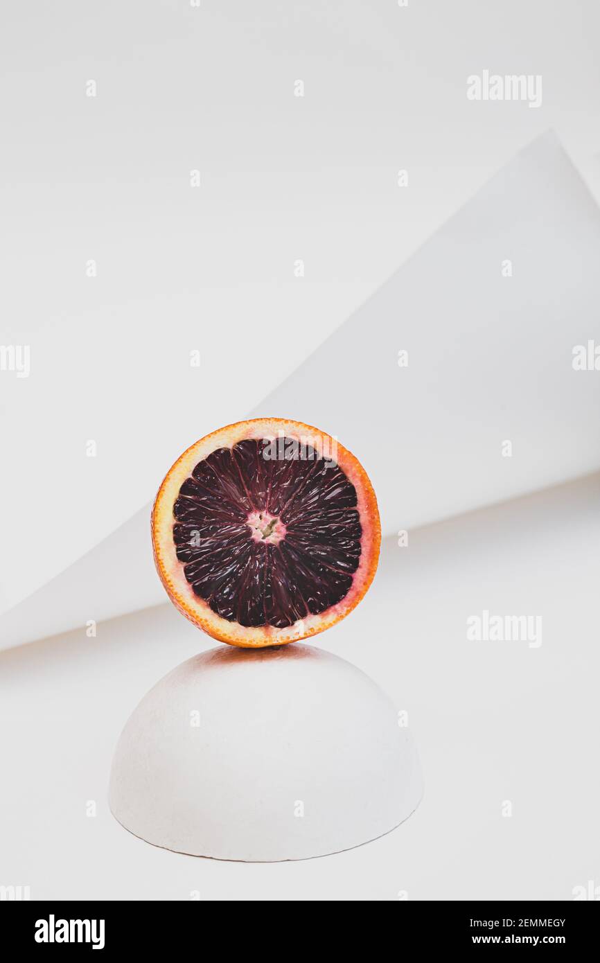 Creative still life with red orange fruits and white geometric shapes ...