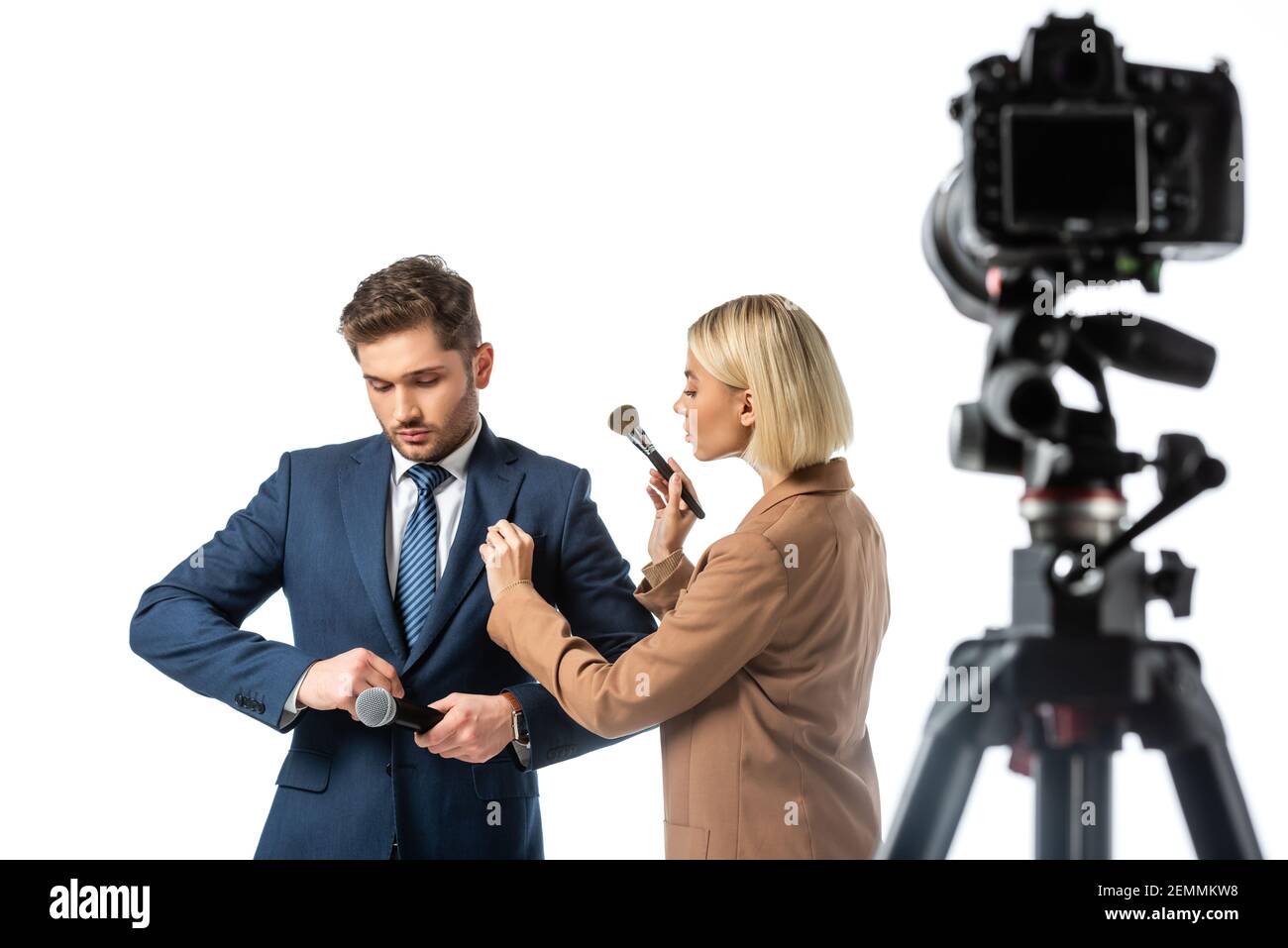 blonde makeup artist with cosmetic brush near news anchor buttoning his ...