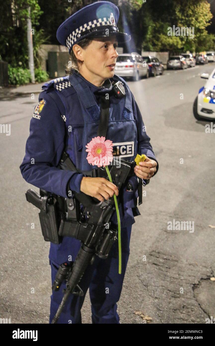 Police officer stands guarding the mosque shooting cordon with a pistol ...