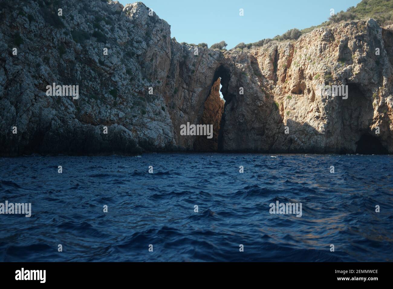 Dark blue sea and rocky cliff with green vegetation Stock Photo - Alamy