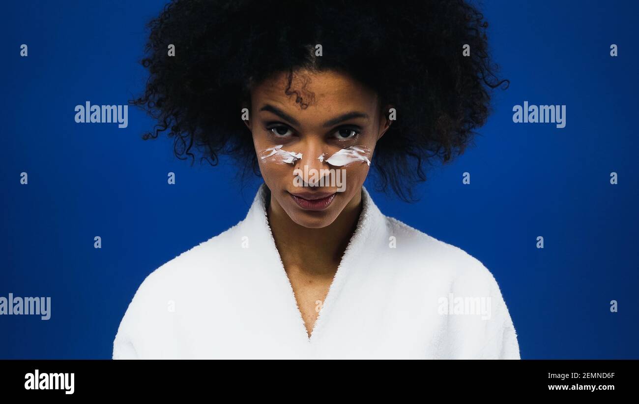 African american woman with face cream isolated on blue Stock Photo - Alamy