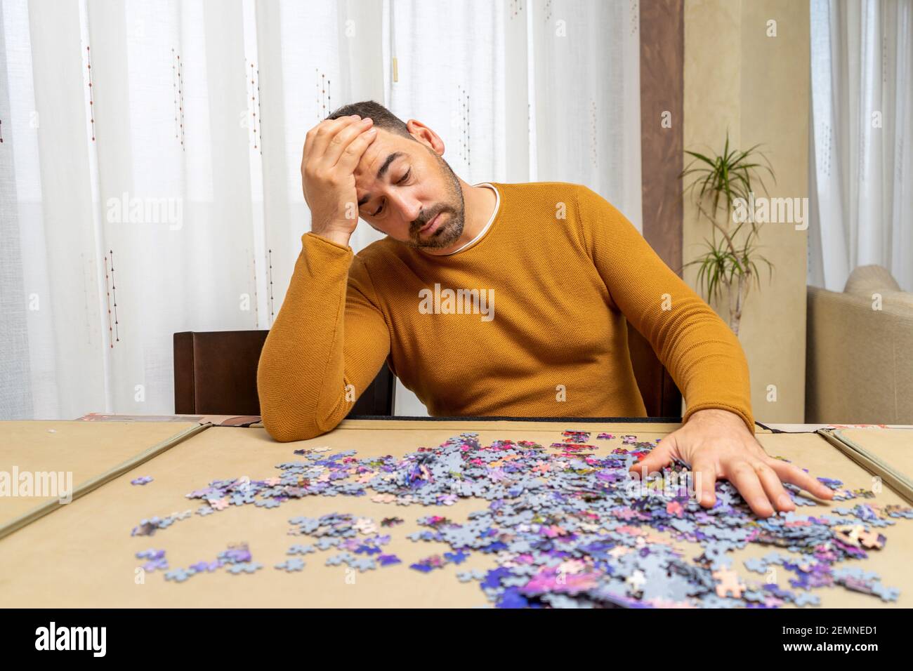 Handsome bearded man in an orange sweater with his hand on his head ...
