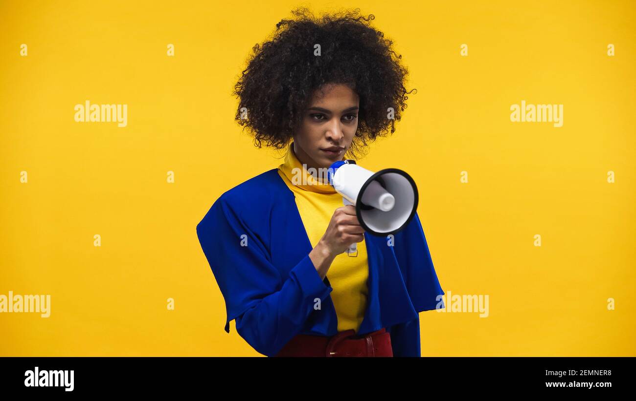 African American Woman Holding Loudspeaker Isolated On Yellow Stock