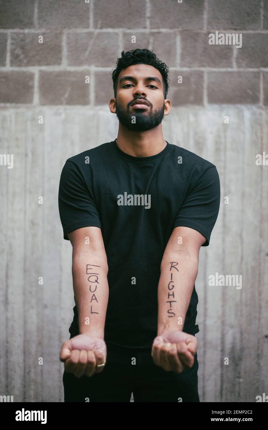 Portrait of male activist showing equal rights written on hand against ...