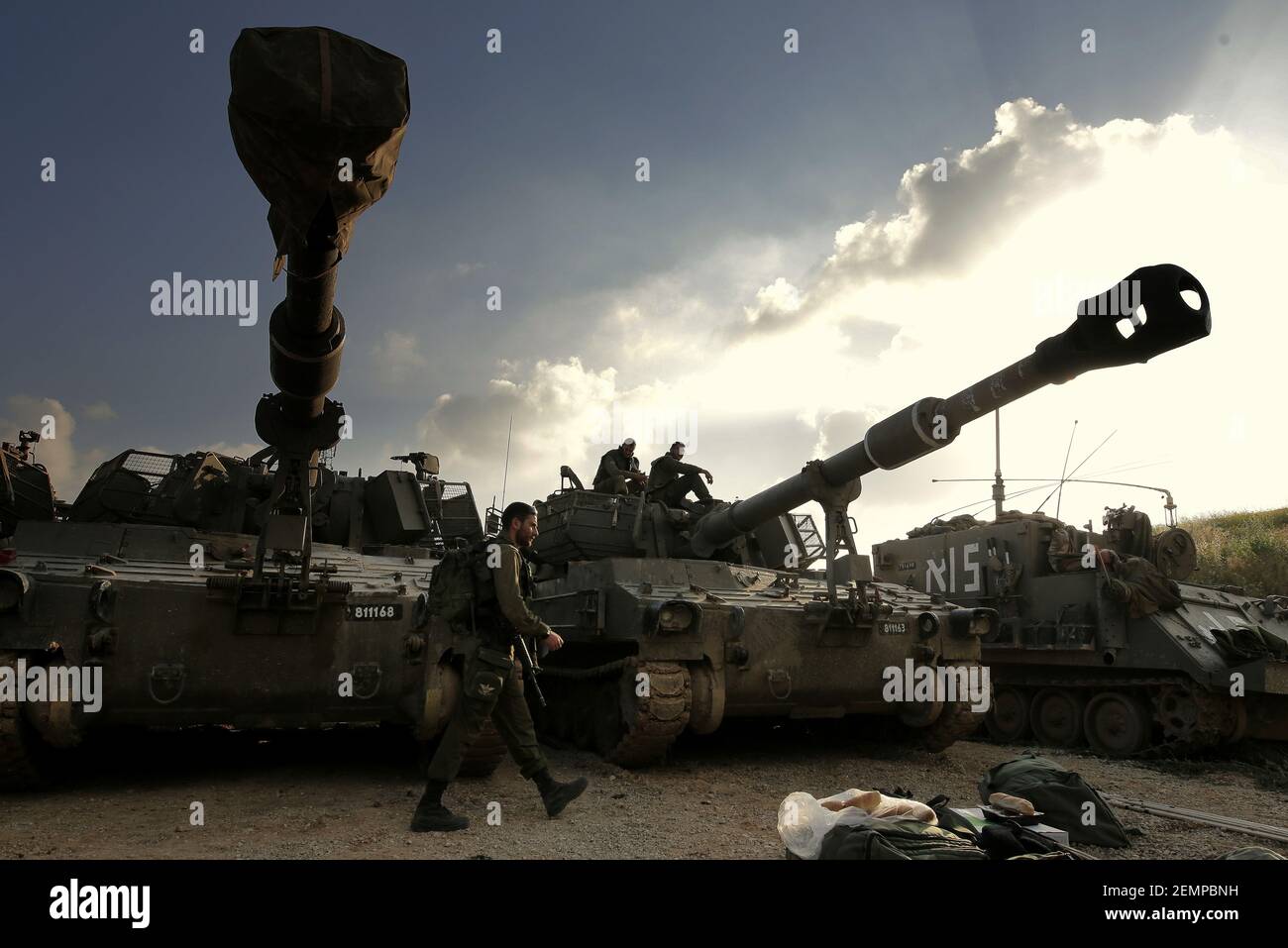 Israeli soldiers are seen next to mobile artillery units near the ...