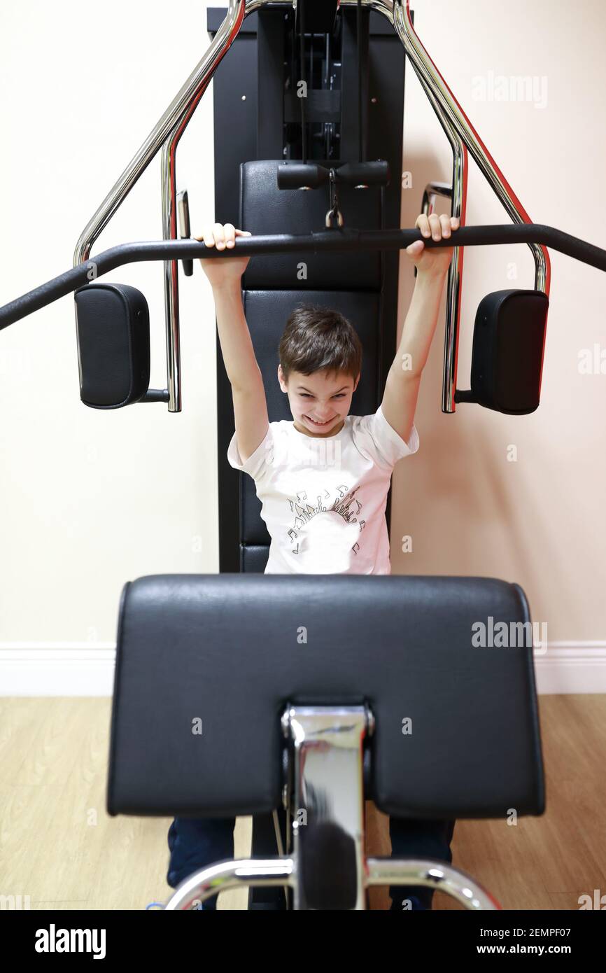Boy doing exercises for back load on simulator in gym Stock Photo - Alamy