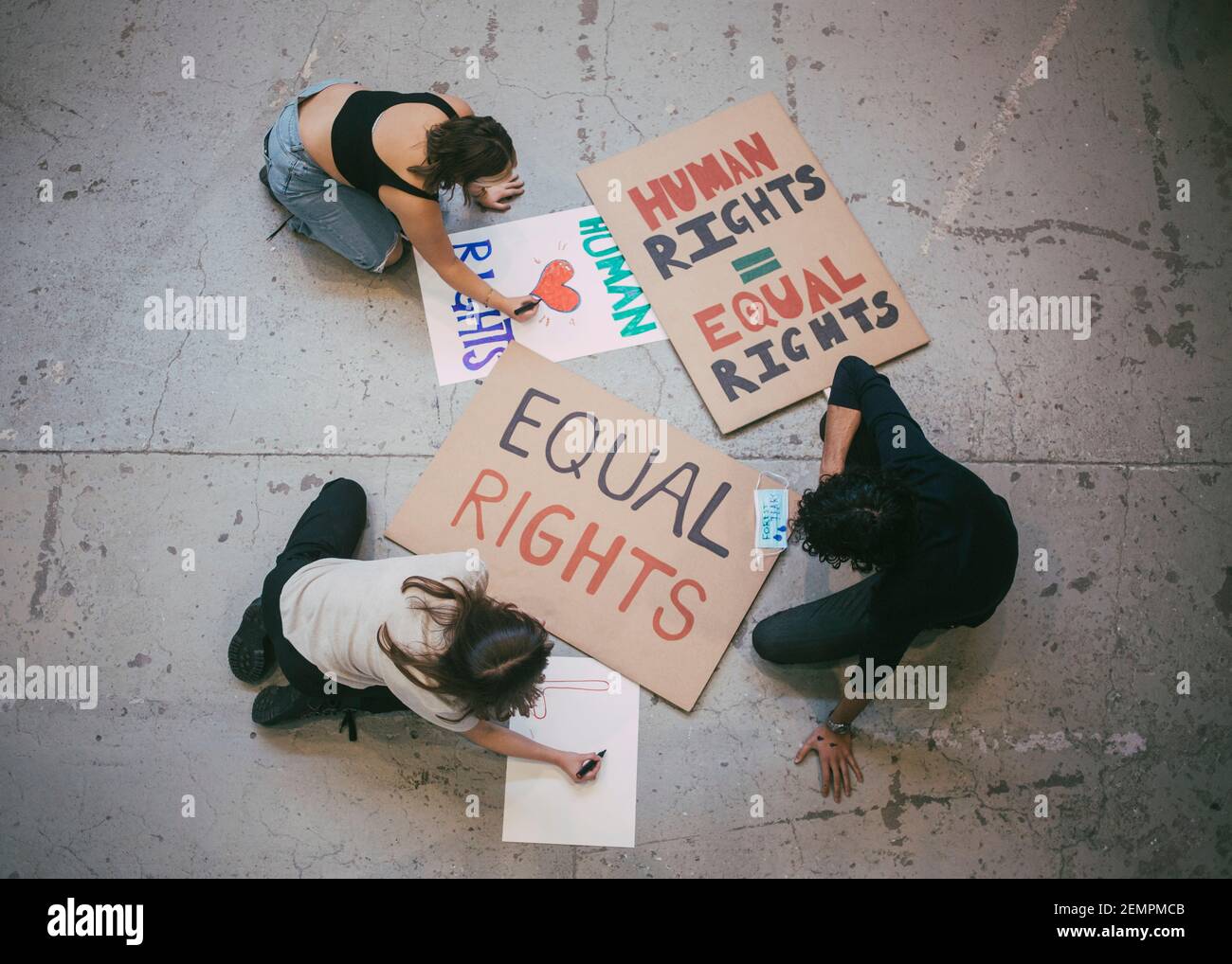 Directly above of male and female activist preparing posters for social ...