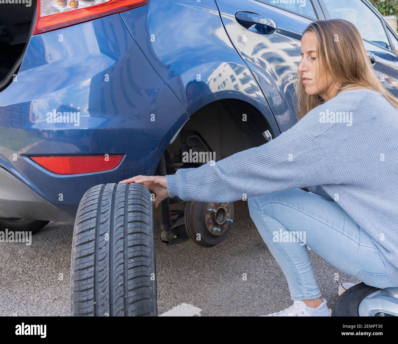 Pretty young woman changing wheel Stock Photo - Alamy
