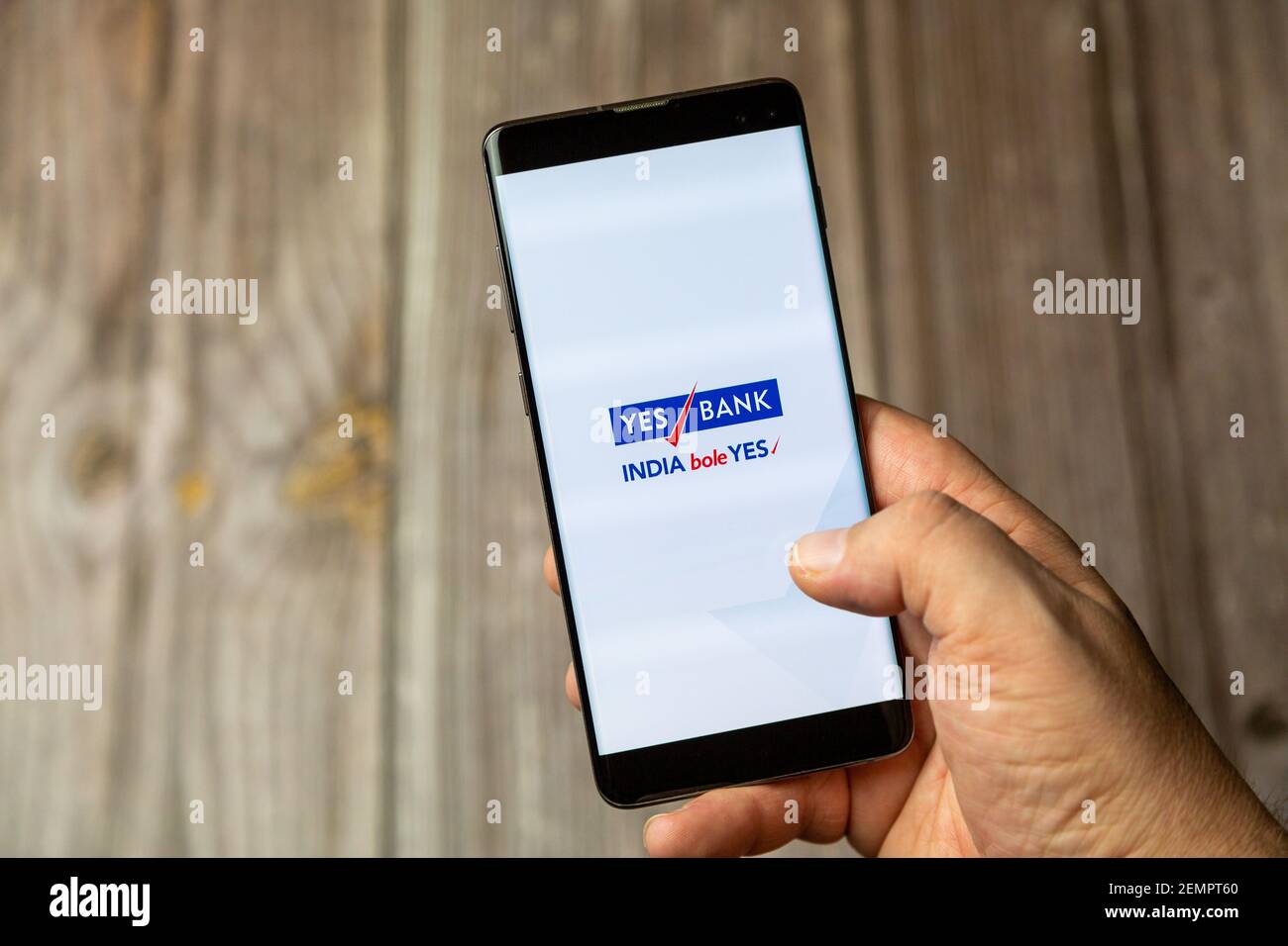 A mobile phone or cell phone being held by a hand with the Yes bank ...