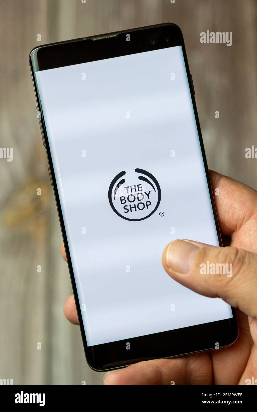 A mobile phone or cell phone being held by a hand with the Body shop ...