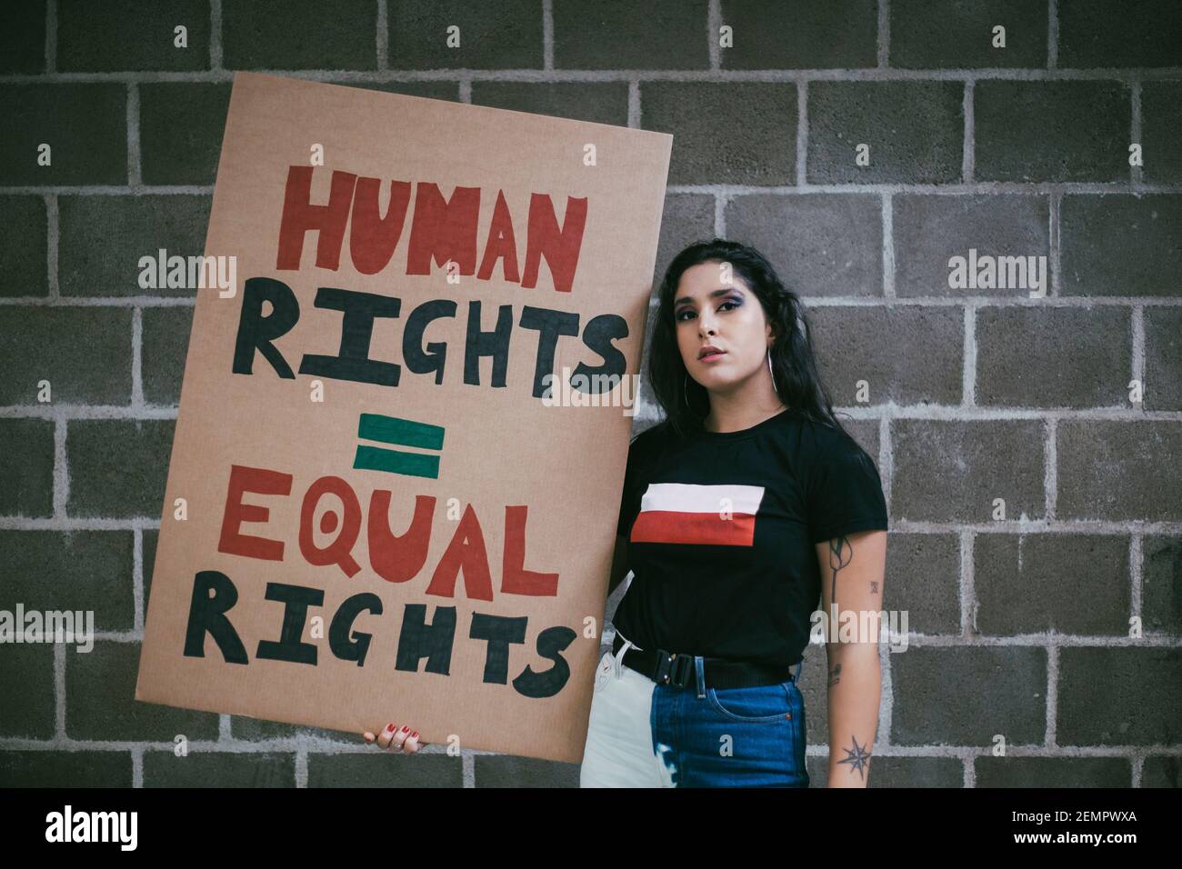 Portrait of female activist with human rights signboard against wall ...