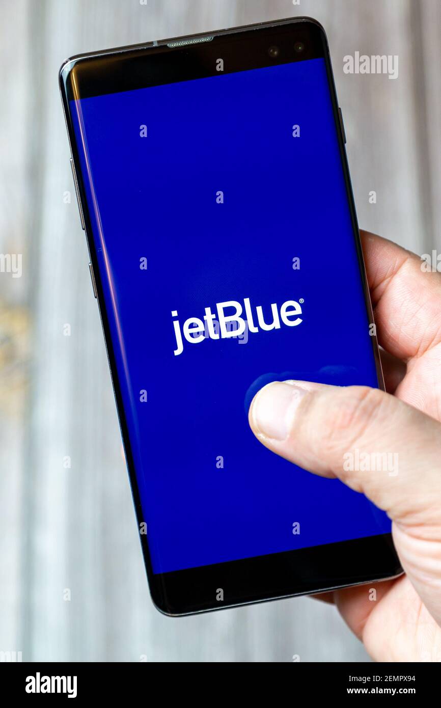 A mobile phone or cell phone being held by a hand with the Jet Blue app ...