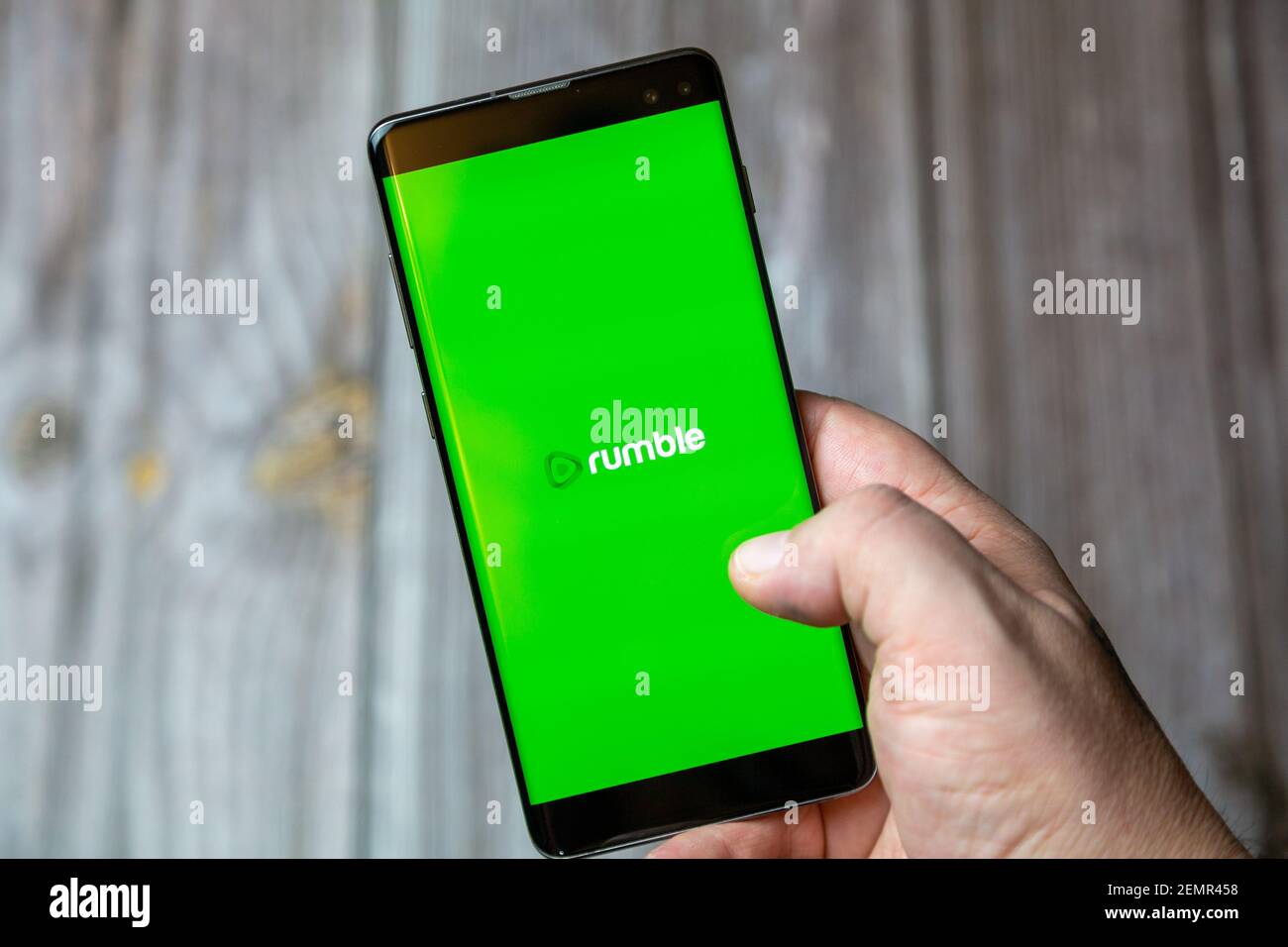 A mobile phone or cell phone being held by a hand with the Rumble app ...