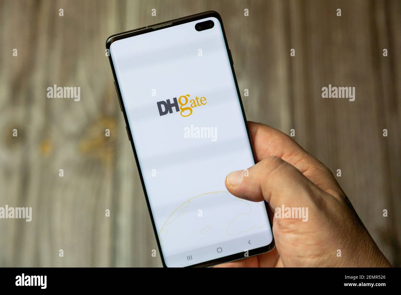 A mobile phone or cell phone being held by a hand with the DH Gate app ...