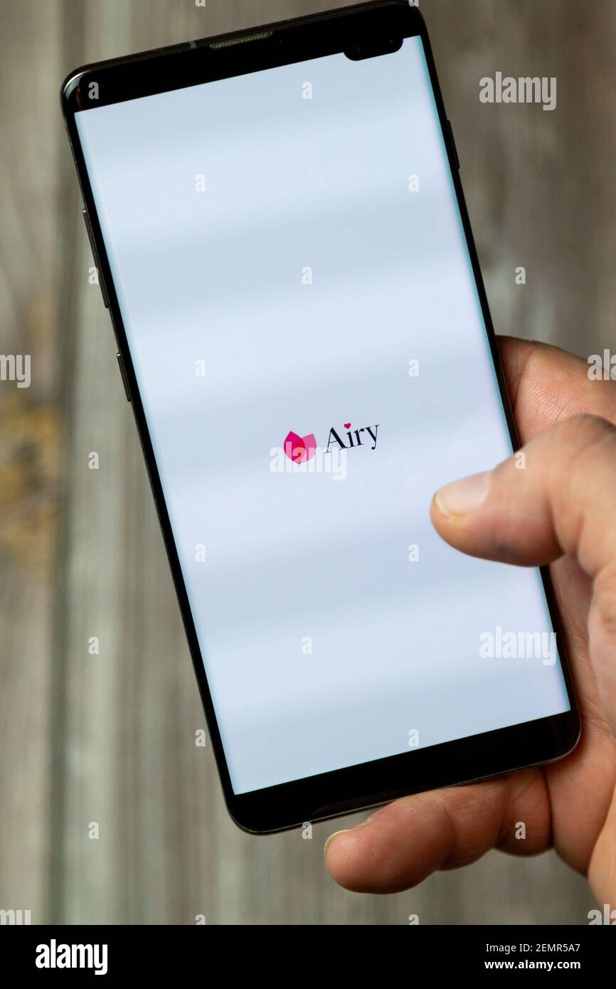 A mobile phone or cell phone being held by a hand with the Airy app ...