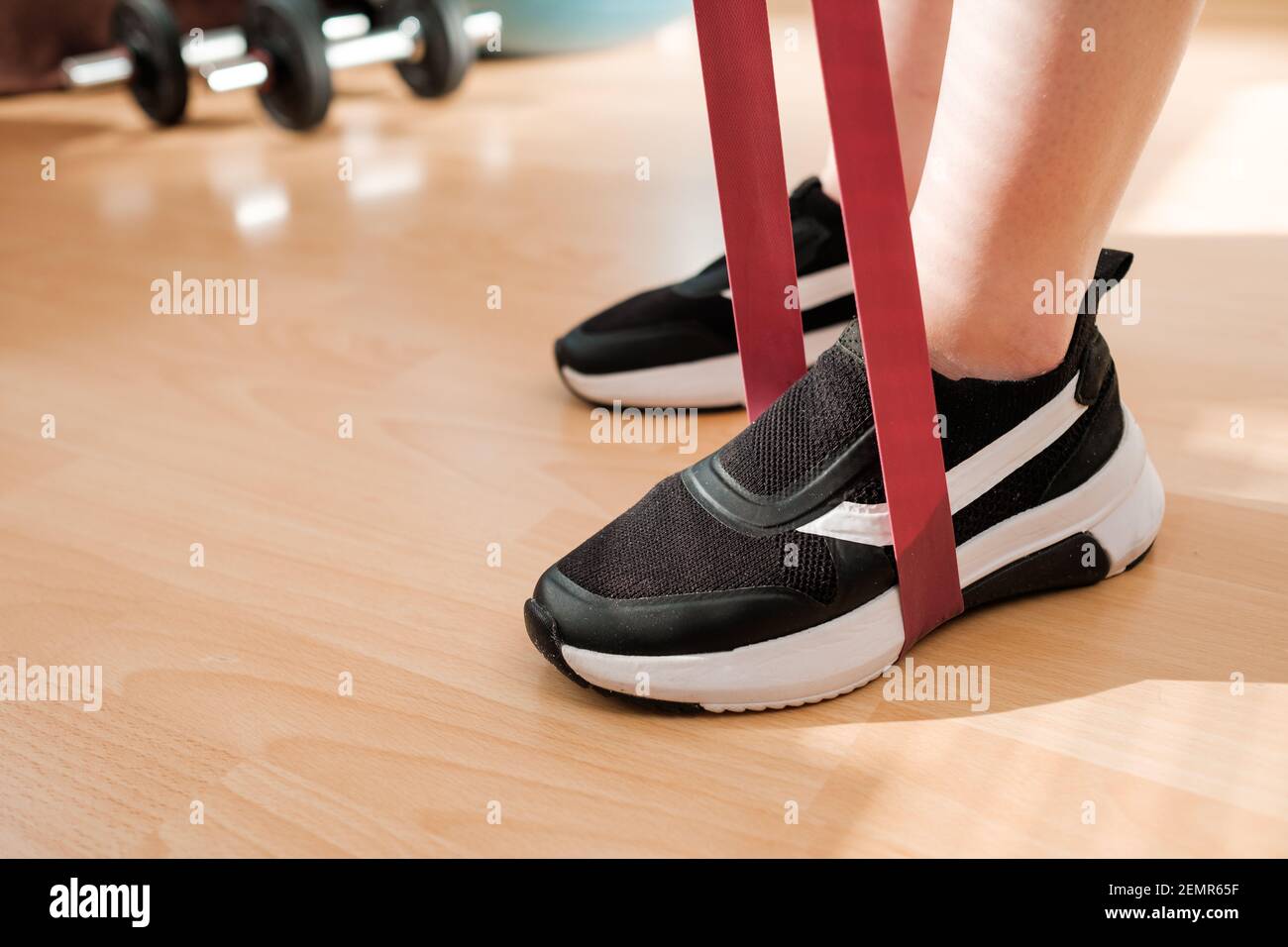 Close up female legs in sneakers doing exercises with fitness elastic ...
